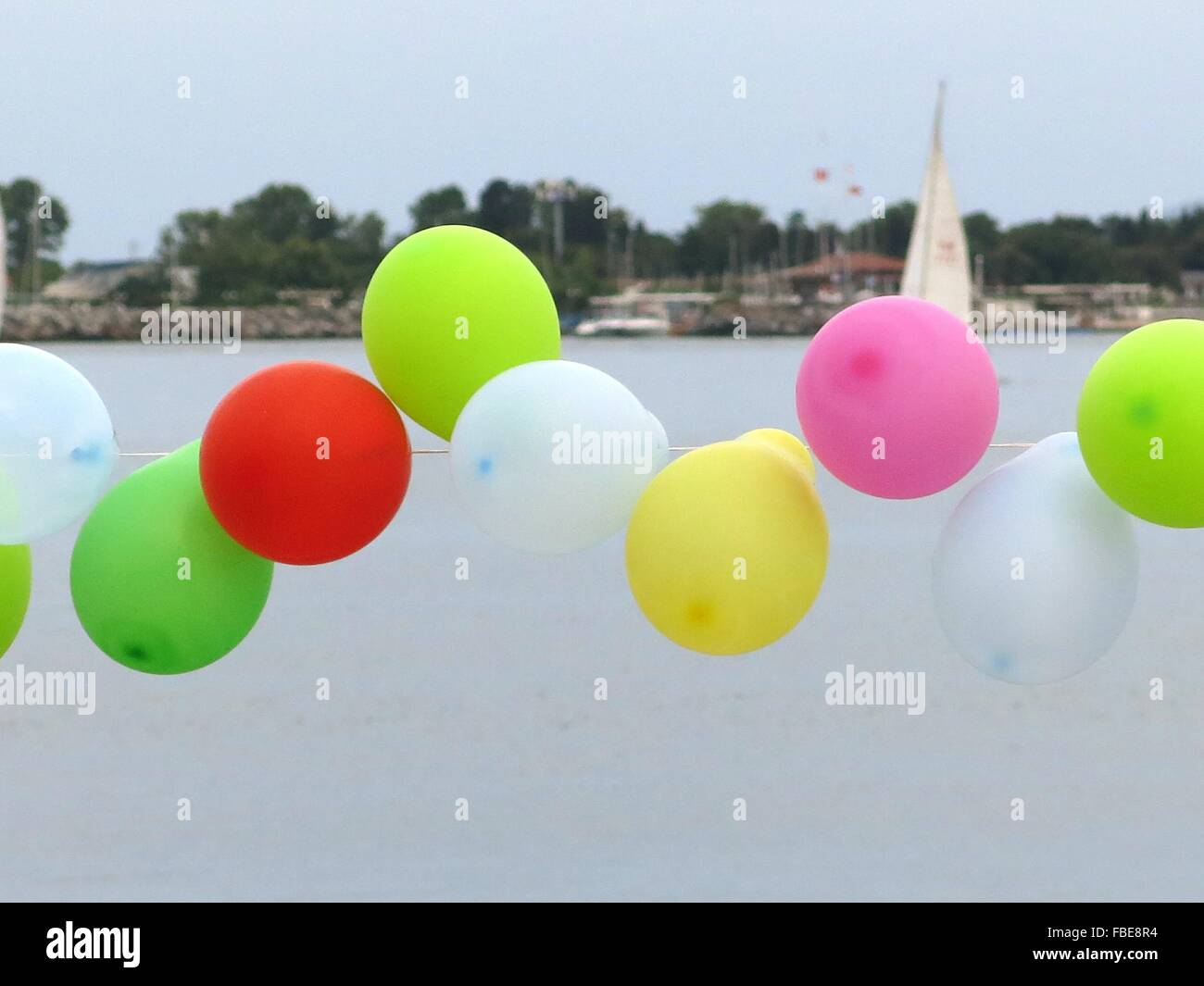 Multi Colored Balloons Tied To Rope Against Sea Stock Photo - Alamy