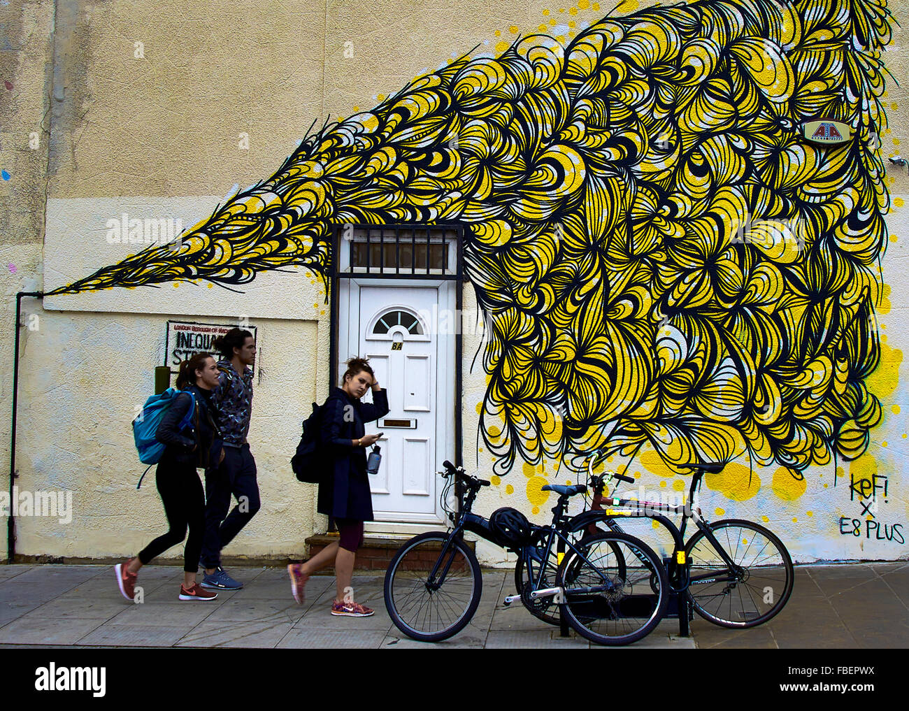 Group of people walking in front of building with graffiti on the wall ...