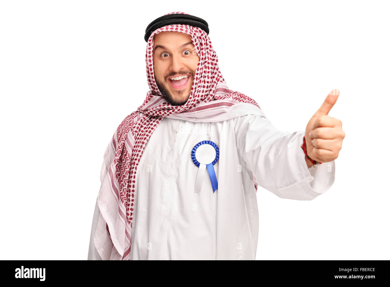 Young cheerful Arab with a blue award ribbon on his robe giving a thumb ...
