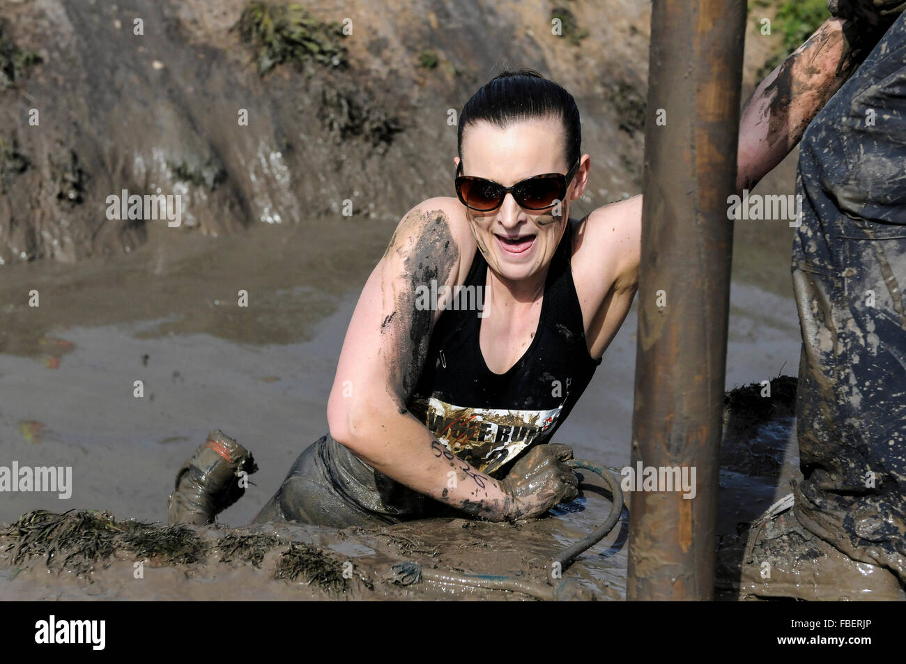 Young female runner helped out of mud pit at obstacle course race, UK ...