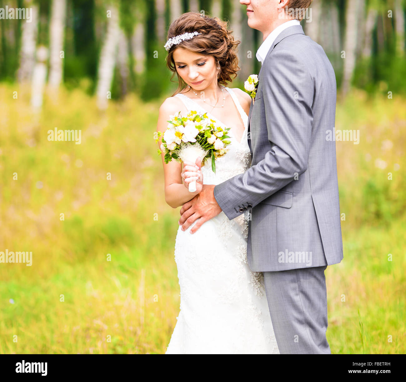young beautiful wedding couple hugging in a field with grass Stock ...