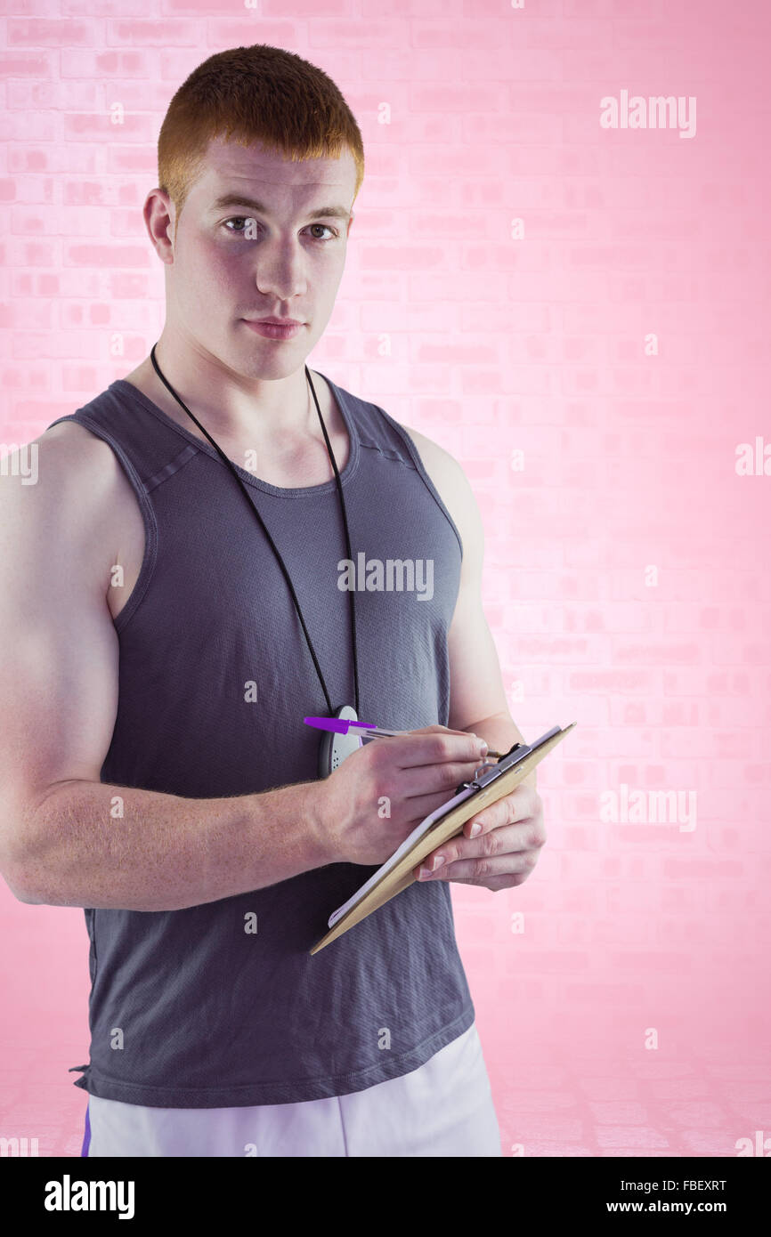 Composite image of fit personal trainer writing on clipboard Stock ...