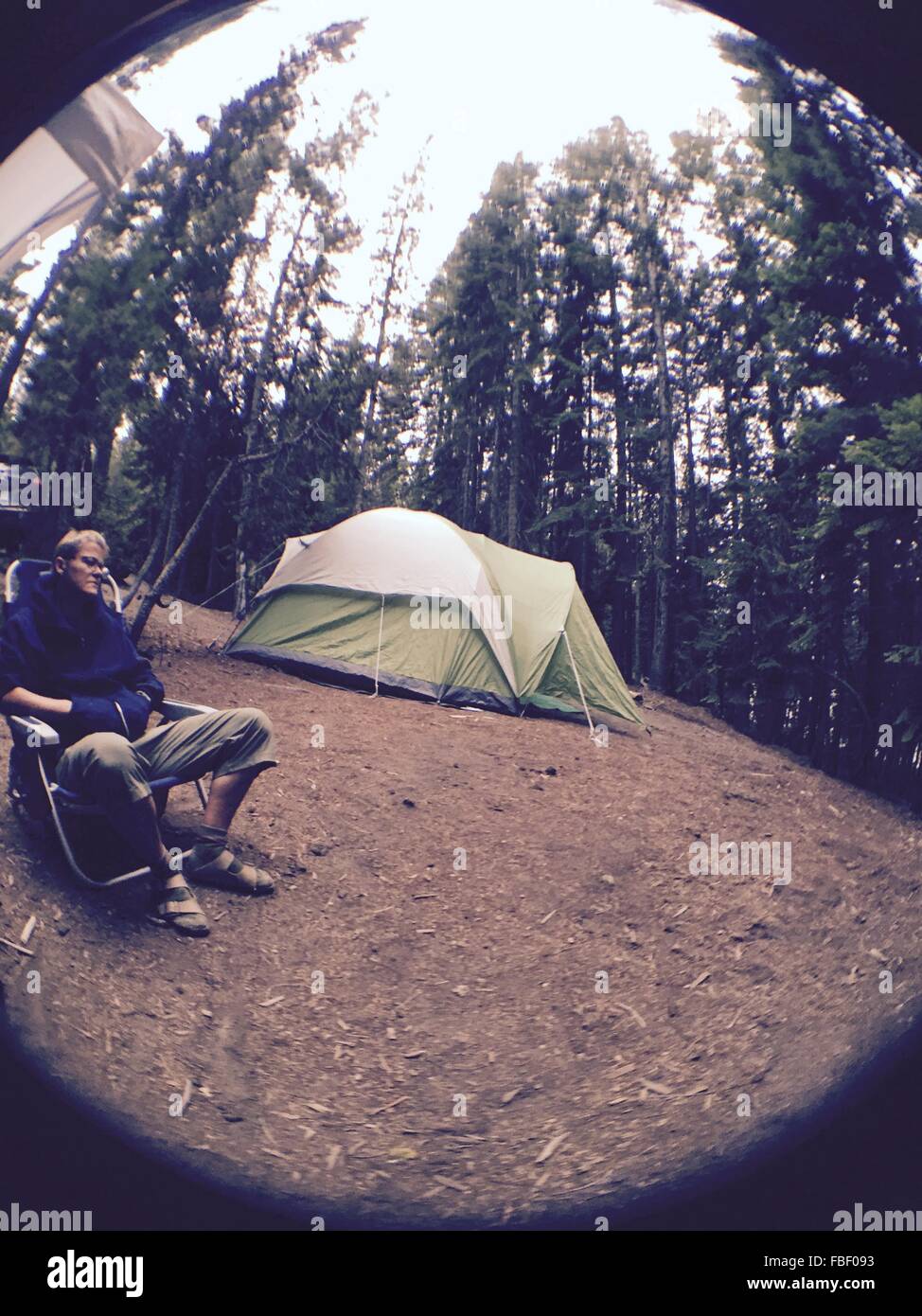 Fish Eye View Of Man Relaxing By Tent At Forest Stock Photo - Alamy