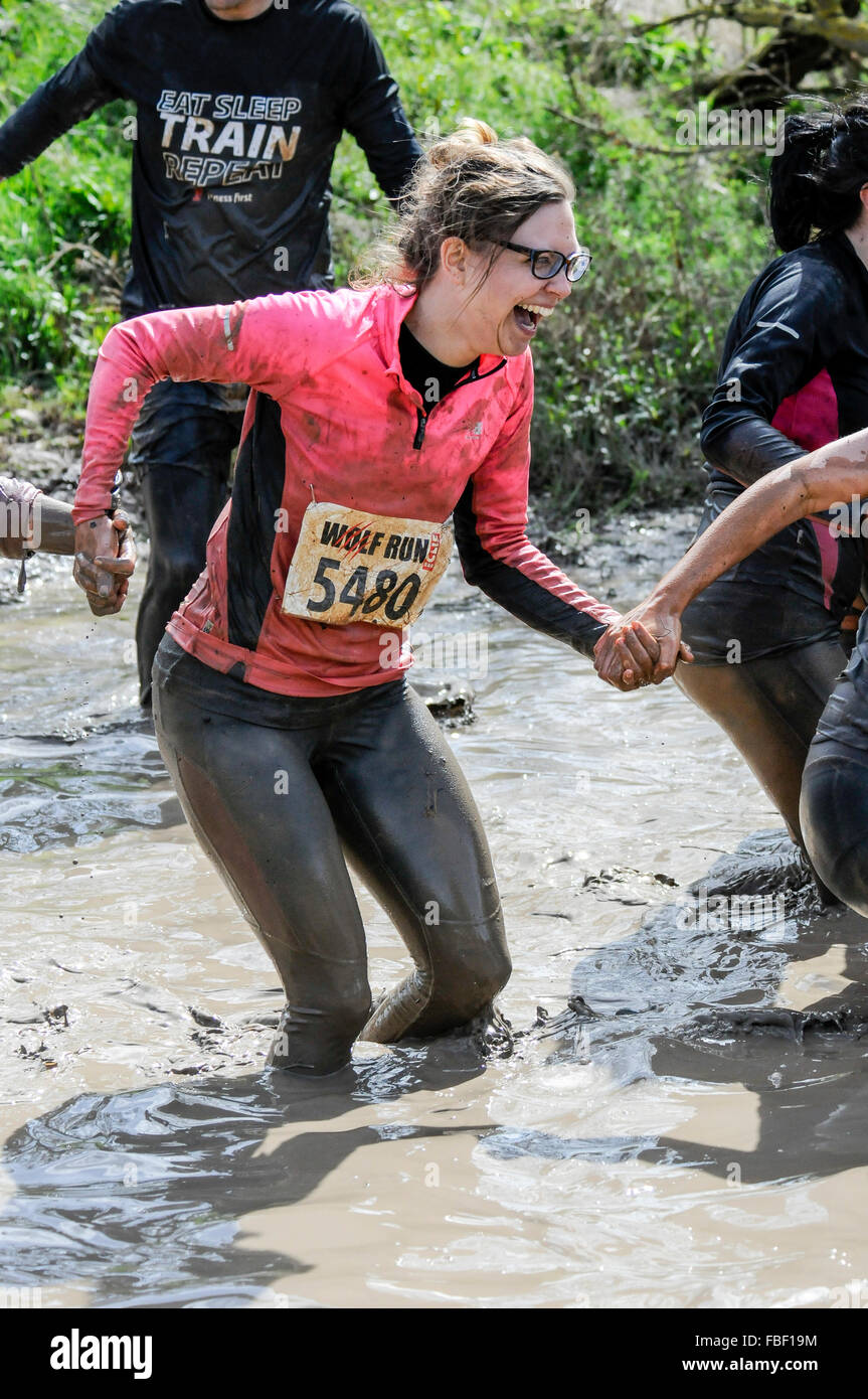 Male and female runners wading through mud lake at obstacle course race ...
