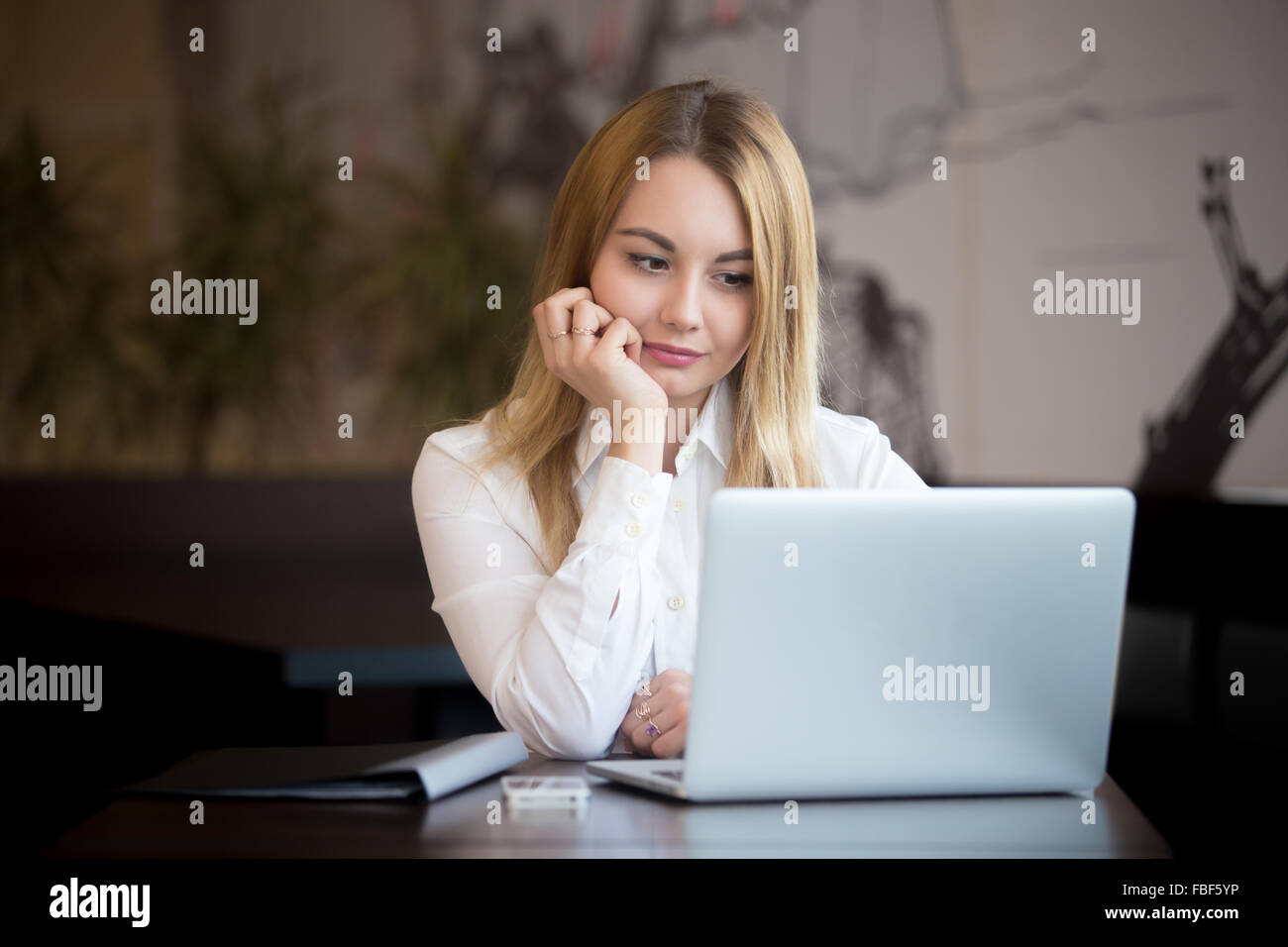 Young beautiful blond caucasian business woman working on laptop ...