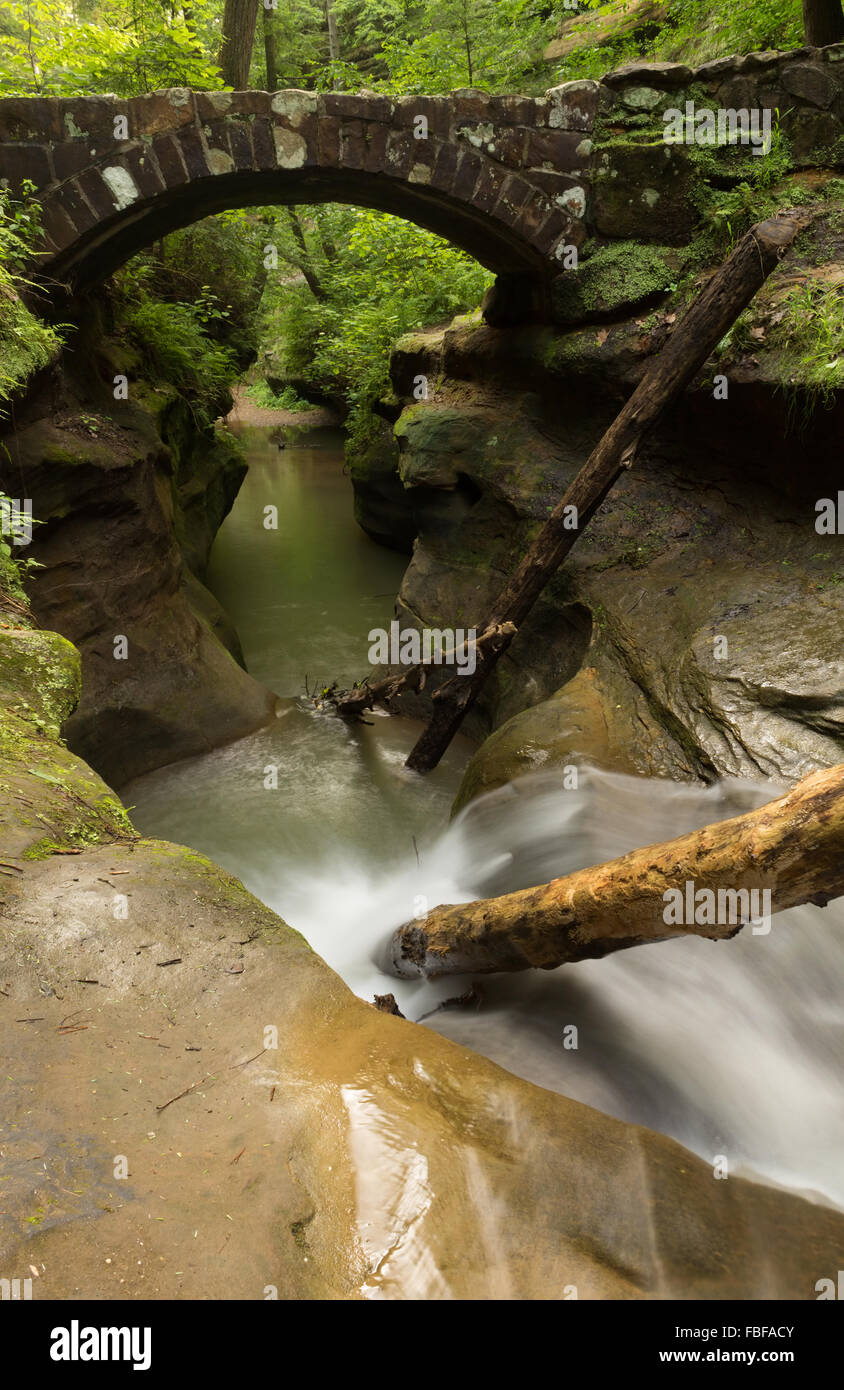 Tranquil stream flowing under a stone bridge at Hocking Hills State ...