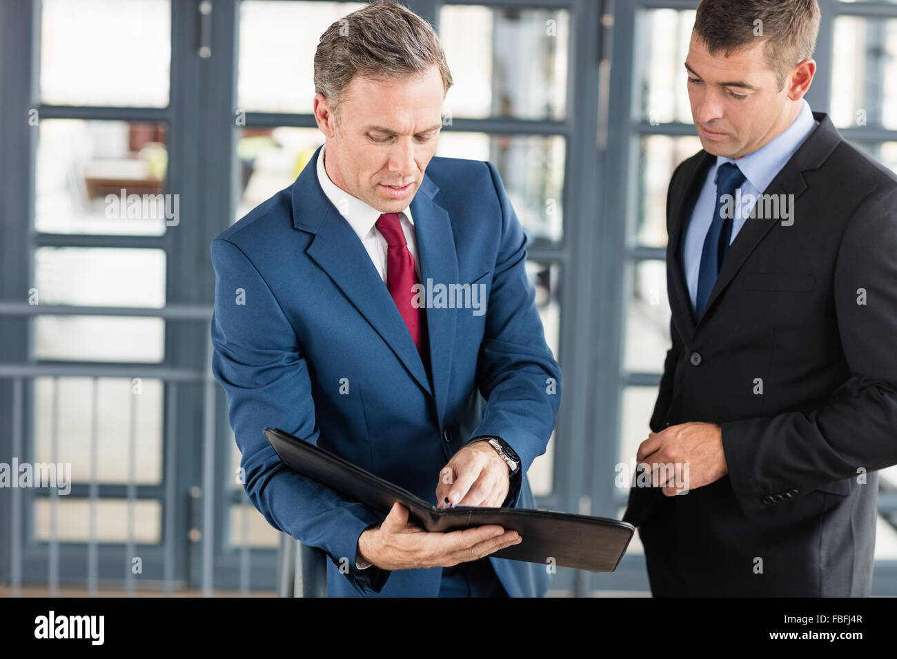 Businessmen talking together while looking folder Stock Photo - Alamy