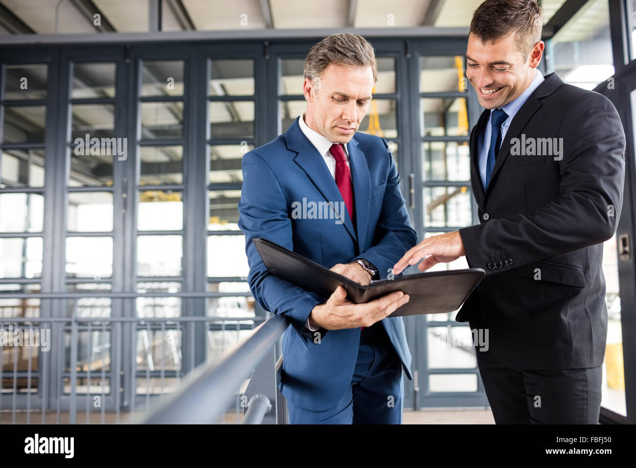 Businessmen talking together while looking folder Stock Photo - Alamy