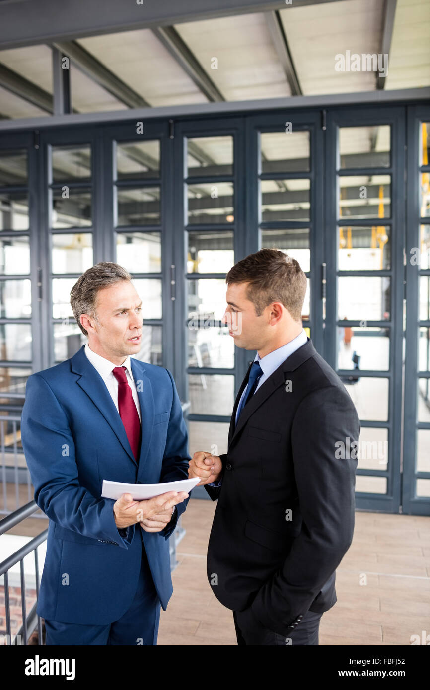 Businessmen talking together while looking folder Stock Photo - Alamy