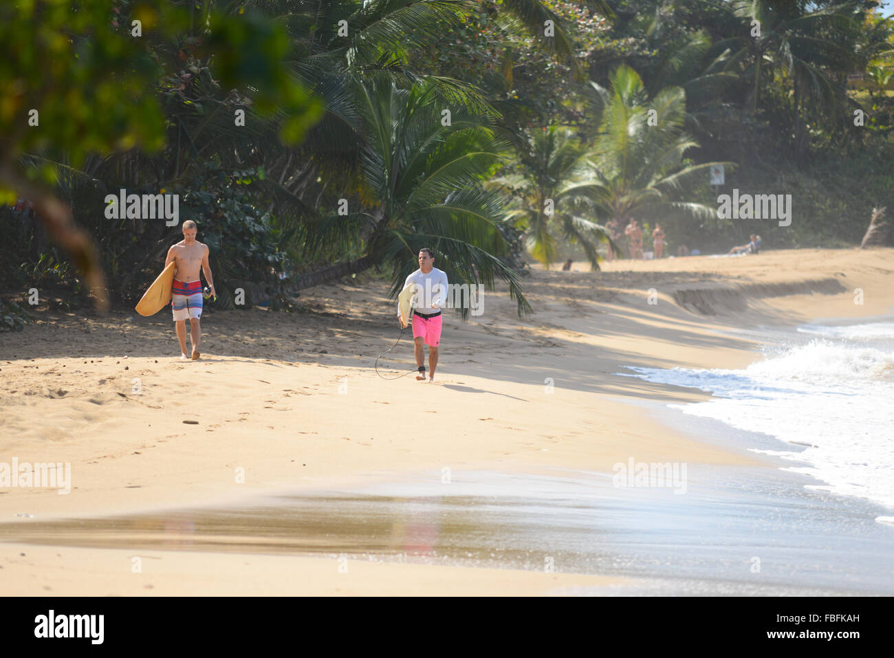 Surfers walking along the shores of Dome's Beach. Rincon, Puerto Rico ...