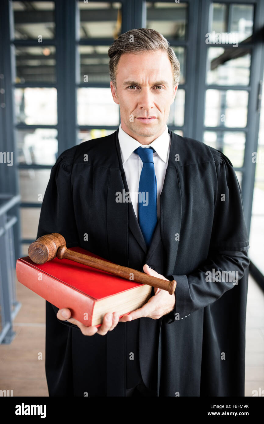 Serious lawyer holding his book and his hammer Stock Photo - Alamy
