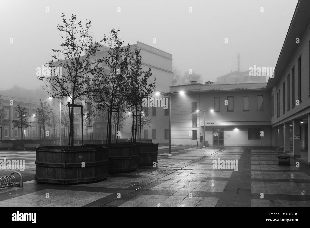 Empty town square in Italy with lights shining through fog surrounded ...