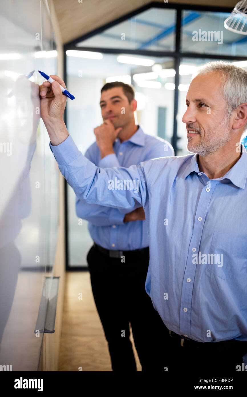 Businessman writing something on board Stock Photo - Alamy