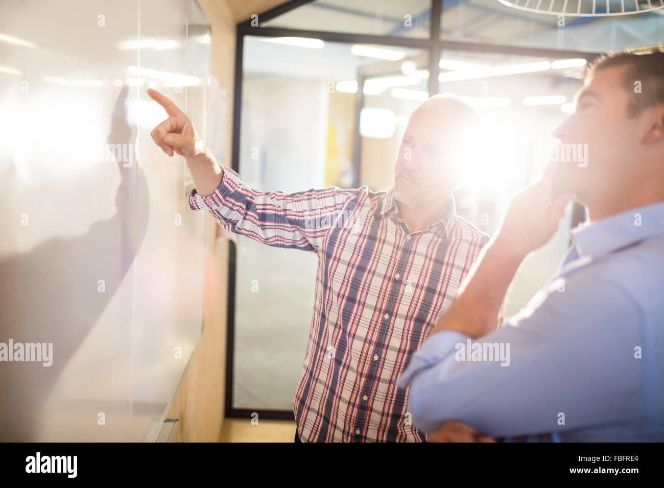 Businessman pointing something on board Stock Photo - Alamy