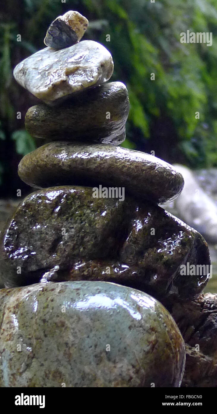 Wet glistening rock stack Cairn in stream with blurred background in ...
