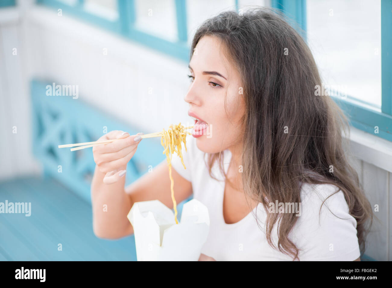 Beautiful young woman, sitting on the bench, holding a fast food lunch ...