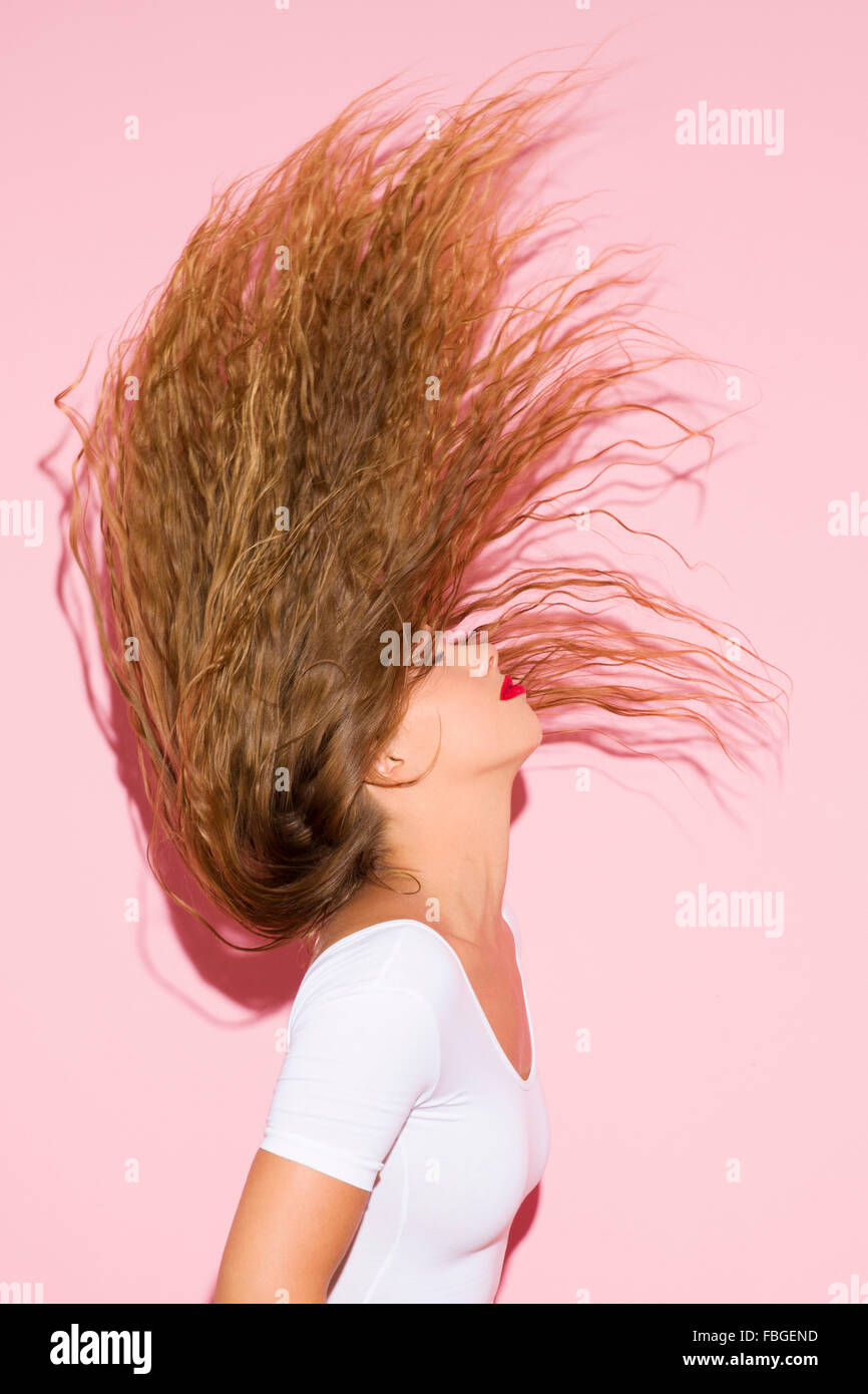 Young woman, head, hair, movement, pink background, side view Stock ...