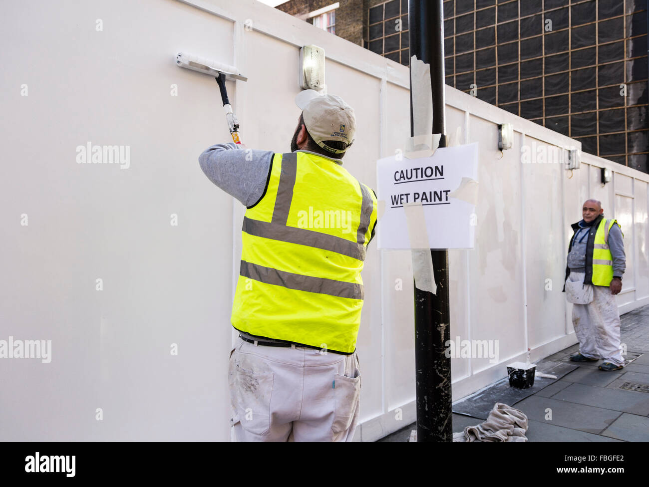 Wet paint - workmen painting a hoarding board in London, UK Stock Photo ...
