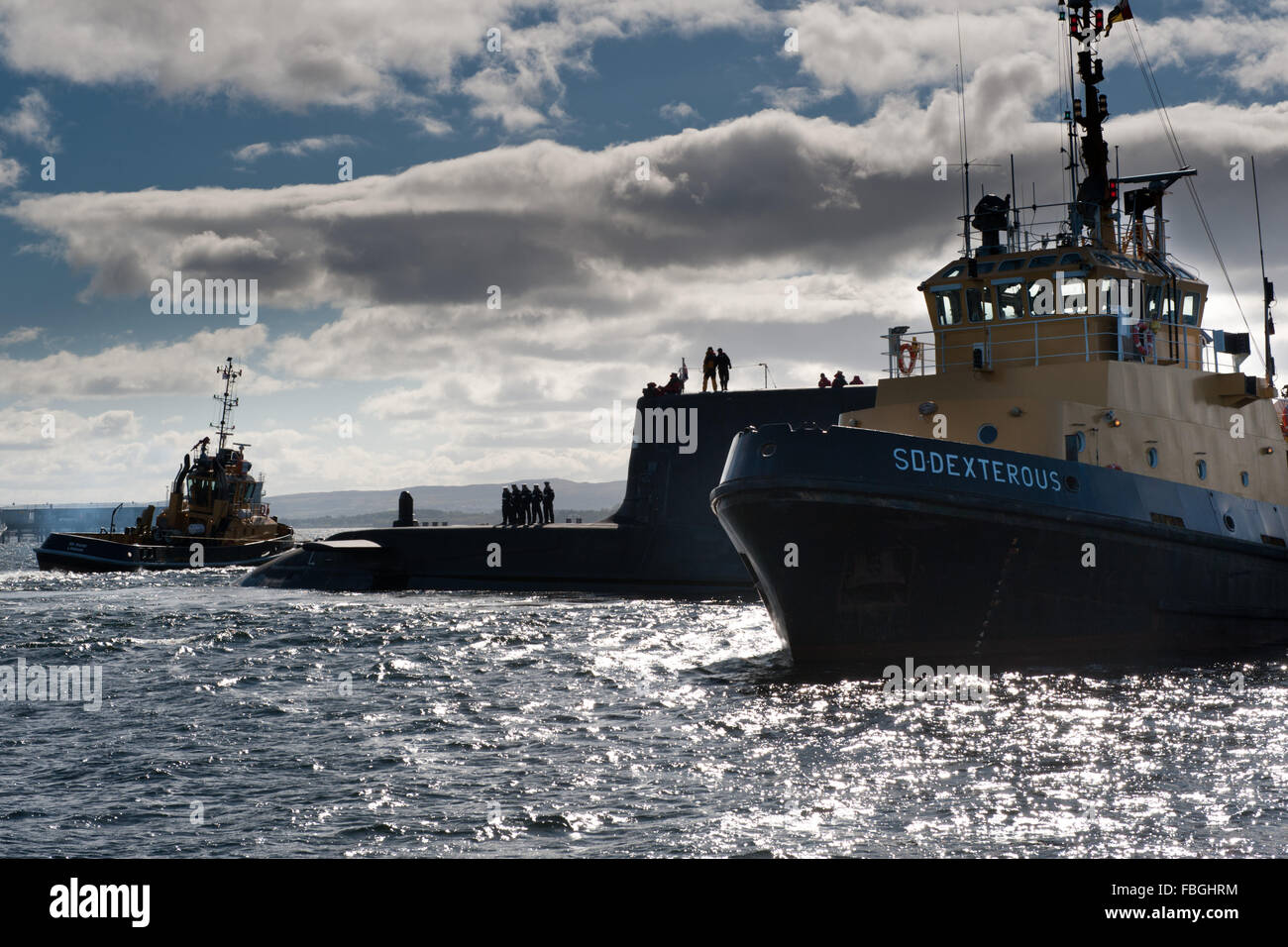Tugboats assisting a nuclear submarine to leave port Stock Photo - Alamy