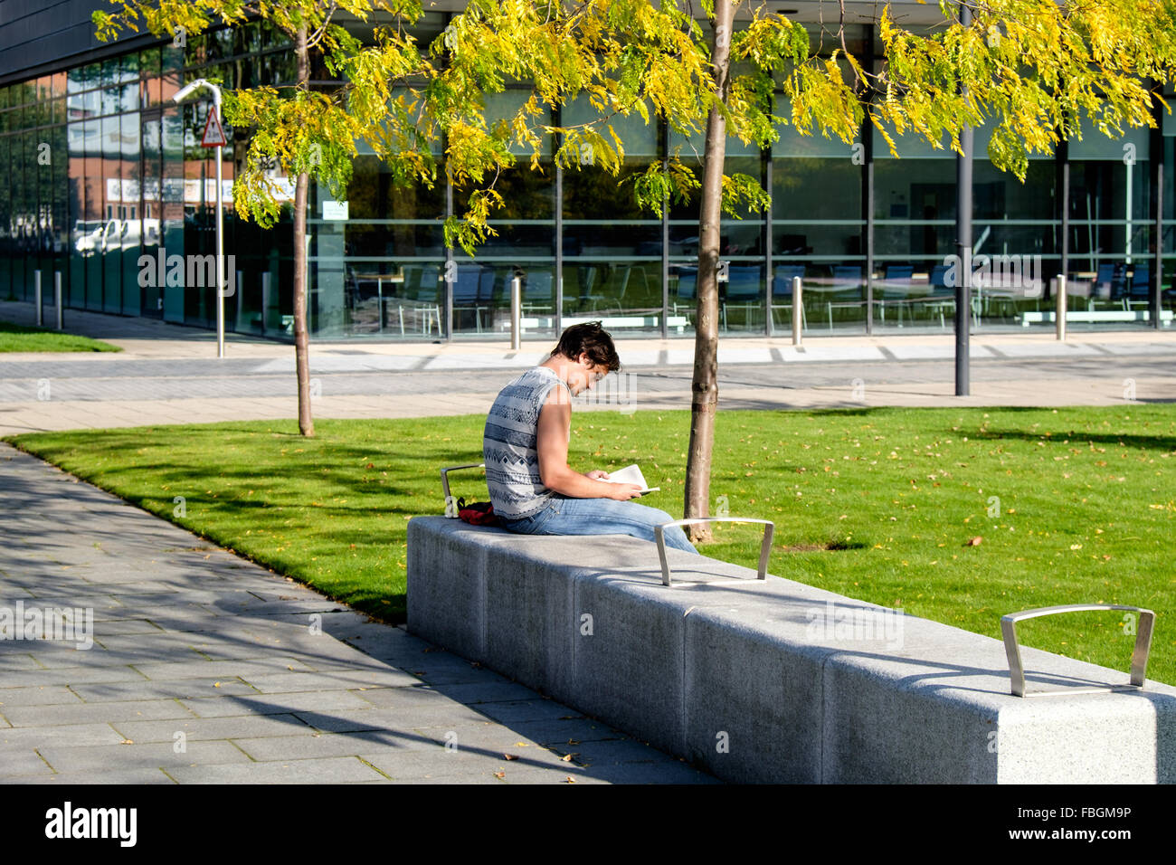 Student sitting on bench and reading outside Alan Turing building, The ...