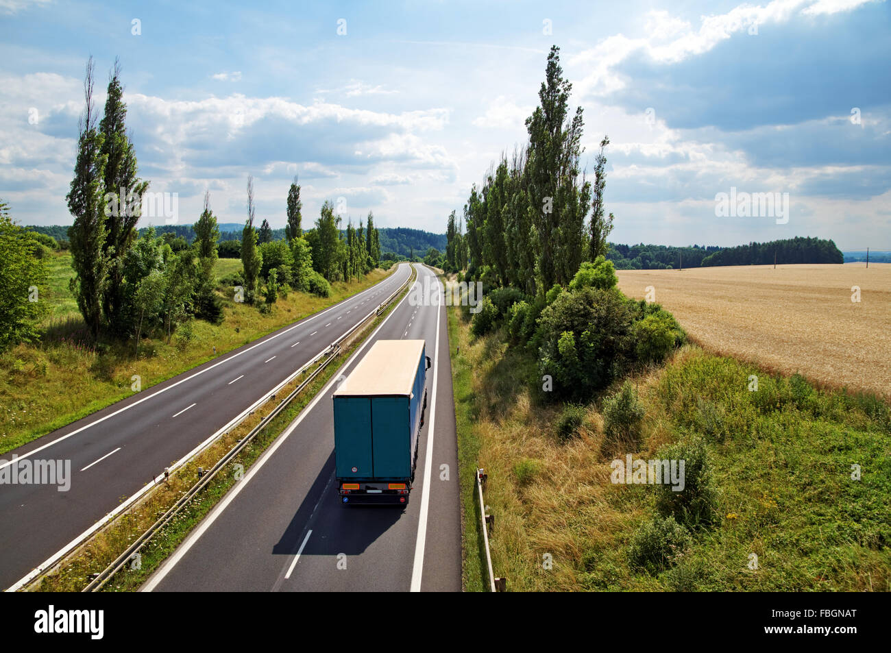 The rural landscape with a highway leading poplar alley, truck driving ...