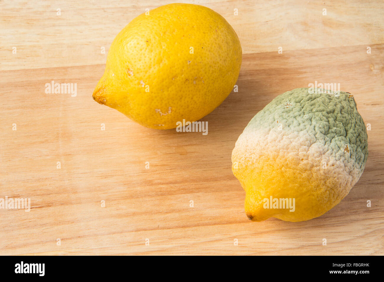 Lemons - one good one rotten - wood background Stock Photo - Alamy