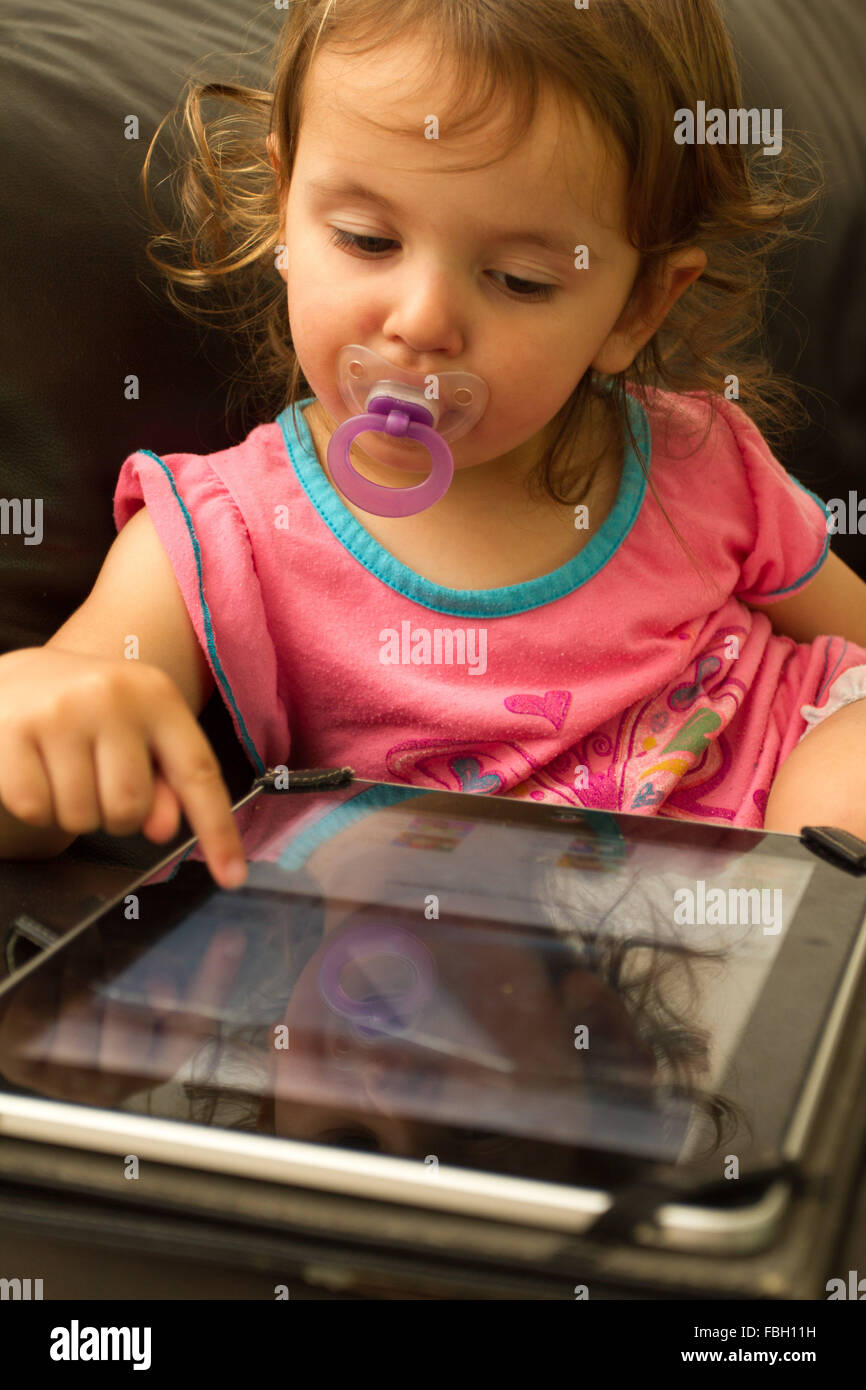Toddler girl wearing pink dress using iPad Stock Photo - Alamy