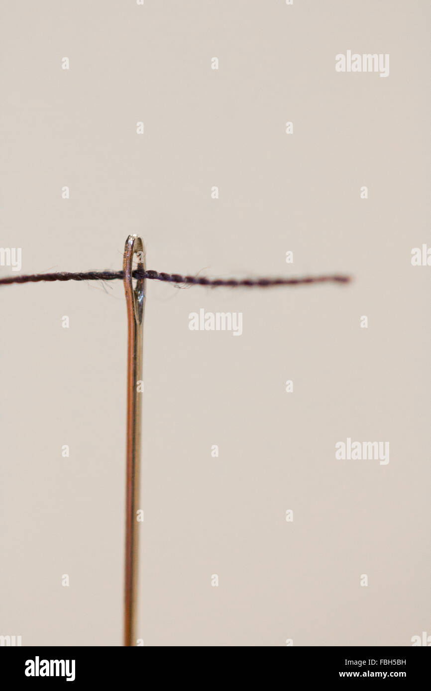 A string being thread through the eye of a needle Stock Photo - Alamy