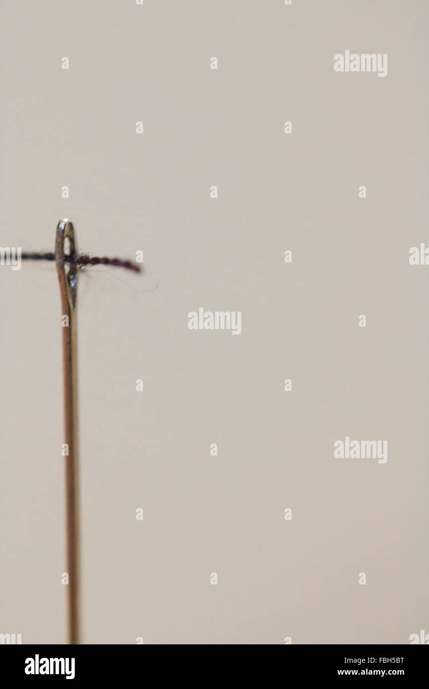 A string being thread through the eye of a needle Stock Photo - Alamy