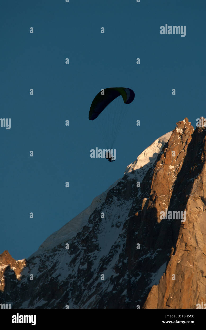 Paraglider pilot with tandem passenger soaring in front of ridge line ...