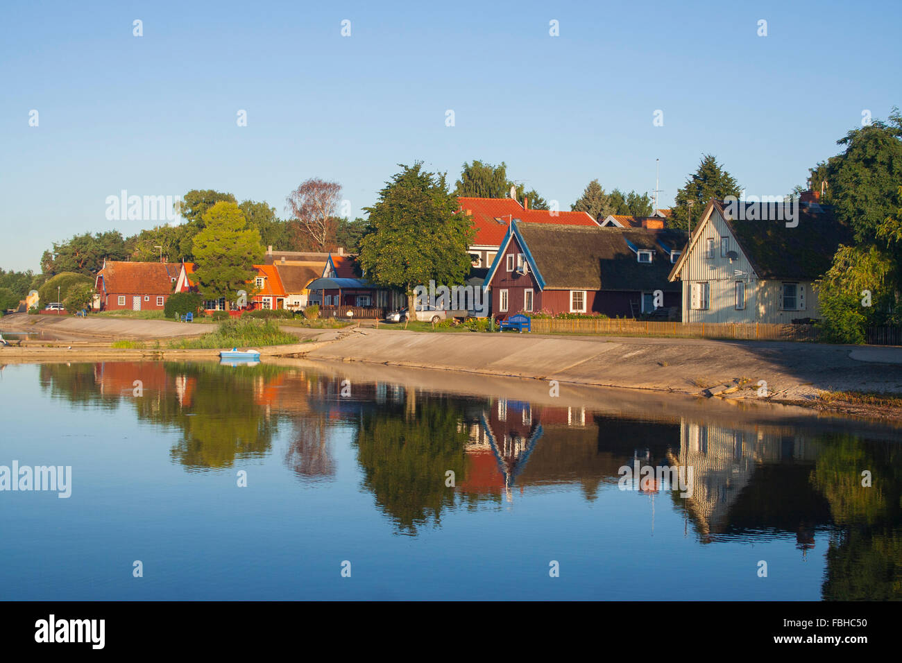 Old Prussian wooden cottages reflected in the Curonian Lagoon in ...