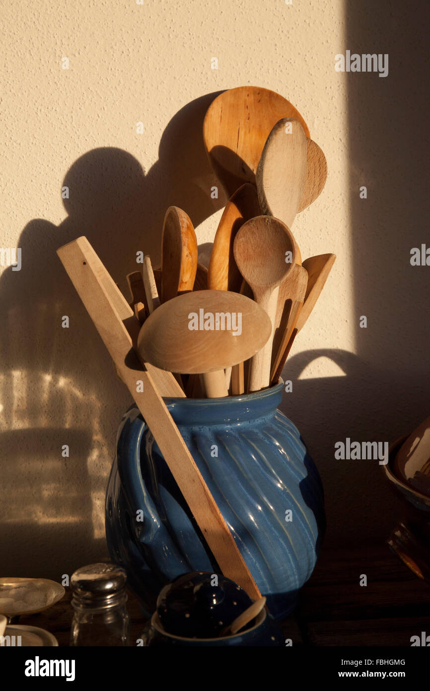 Kitchen utensils, wooden spoon in earthenware jug, morning light ...