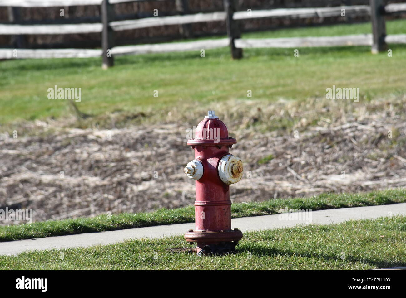 A rusty fire hydrant next to a sidewalk, grass, fence Stock Photo - Alamy