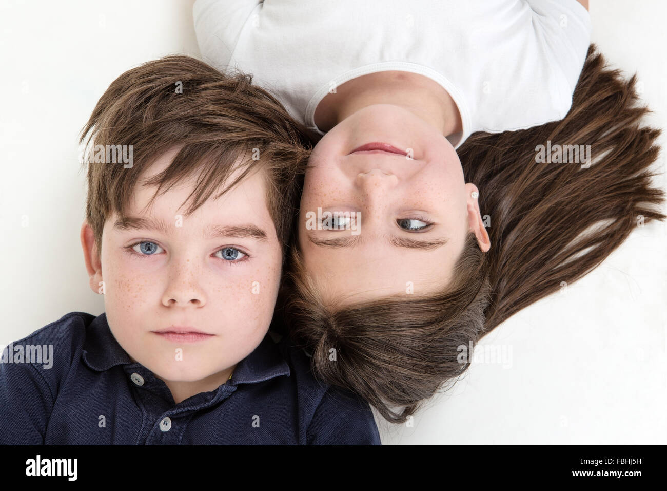 Overhead shot of two children laying on the floor looking up Stock ...