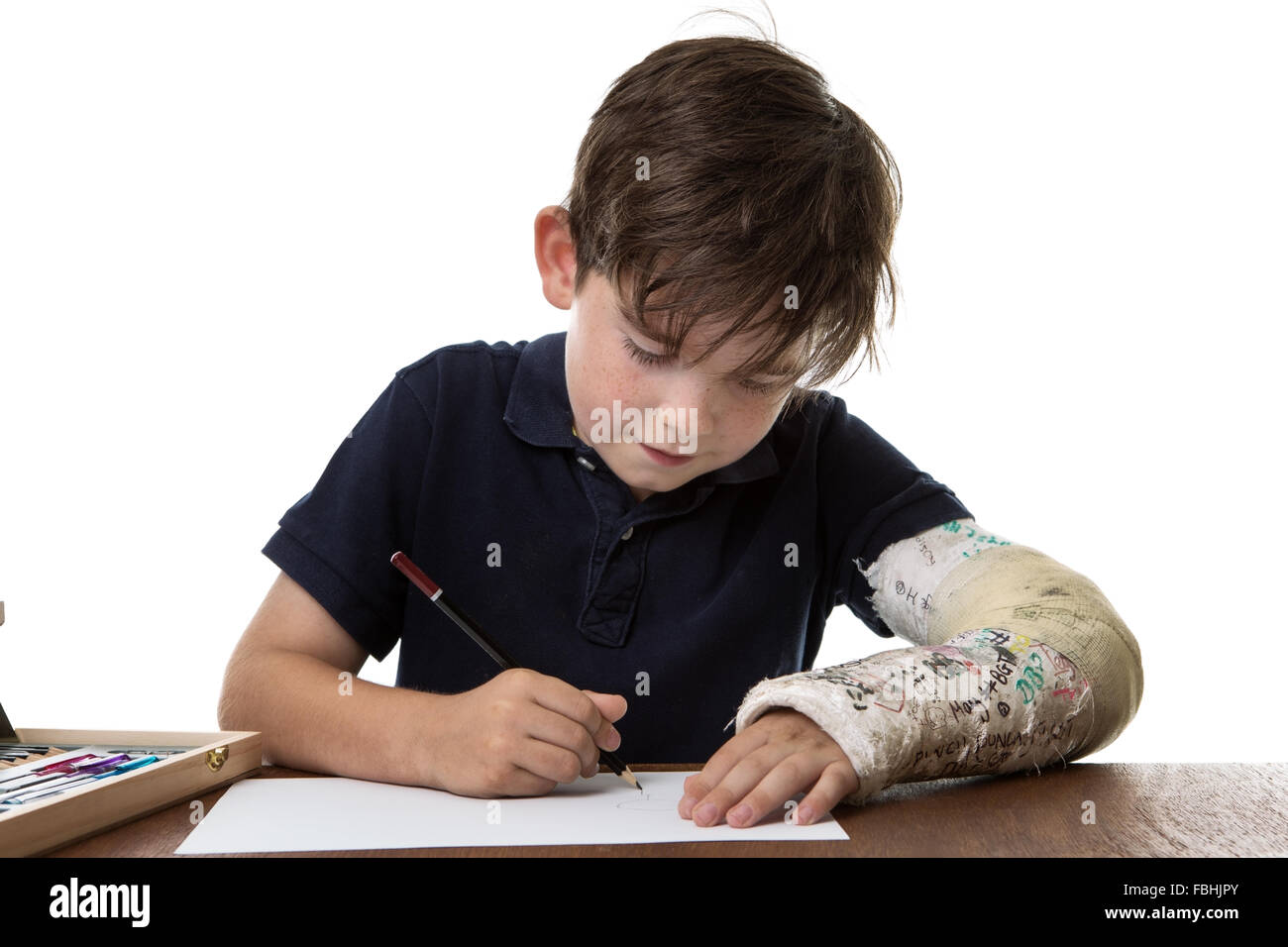 young boy drawing a picture , whilst he has a broken left arm Stock ...