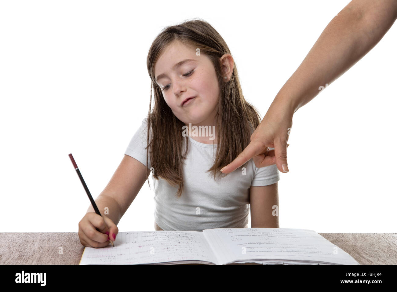 Young girl writing in a book with her mums finger pointing at her work ...