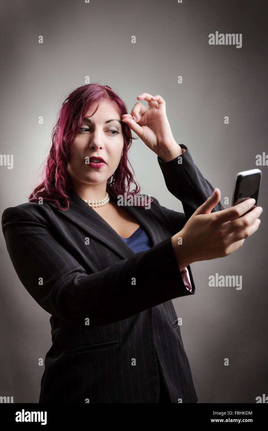 Business woman fixing her hair and holding her mobile phone in the ...