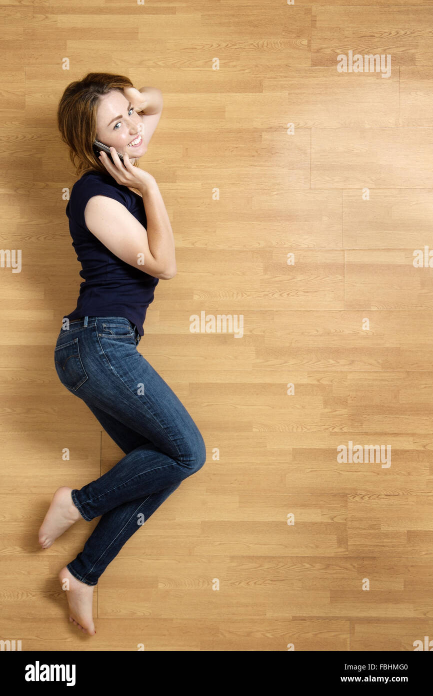 Smiling woman lying on her left hand side on the floor, resting on her ...