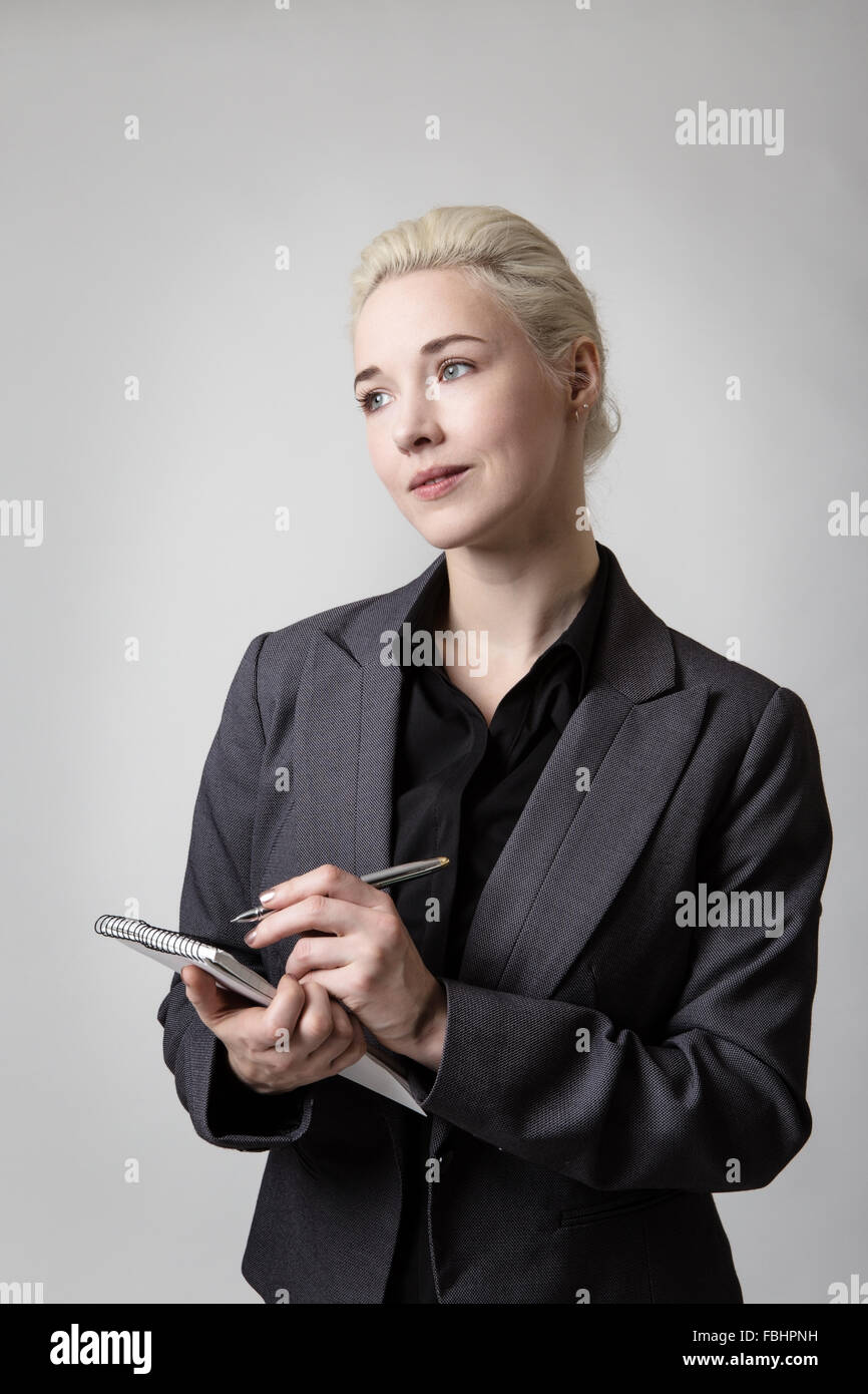 Model holding a spiral notepad and pen, poised to write Stock Photo - Alamy