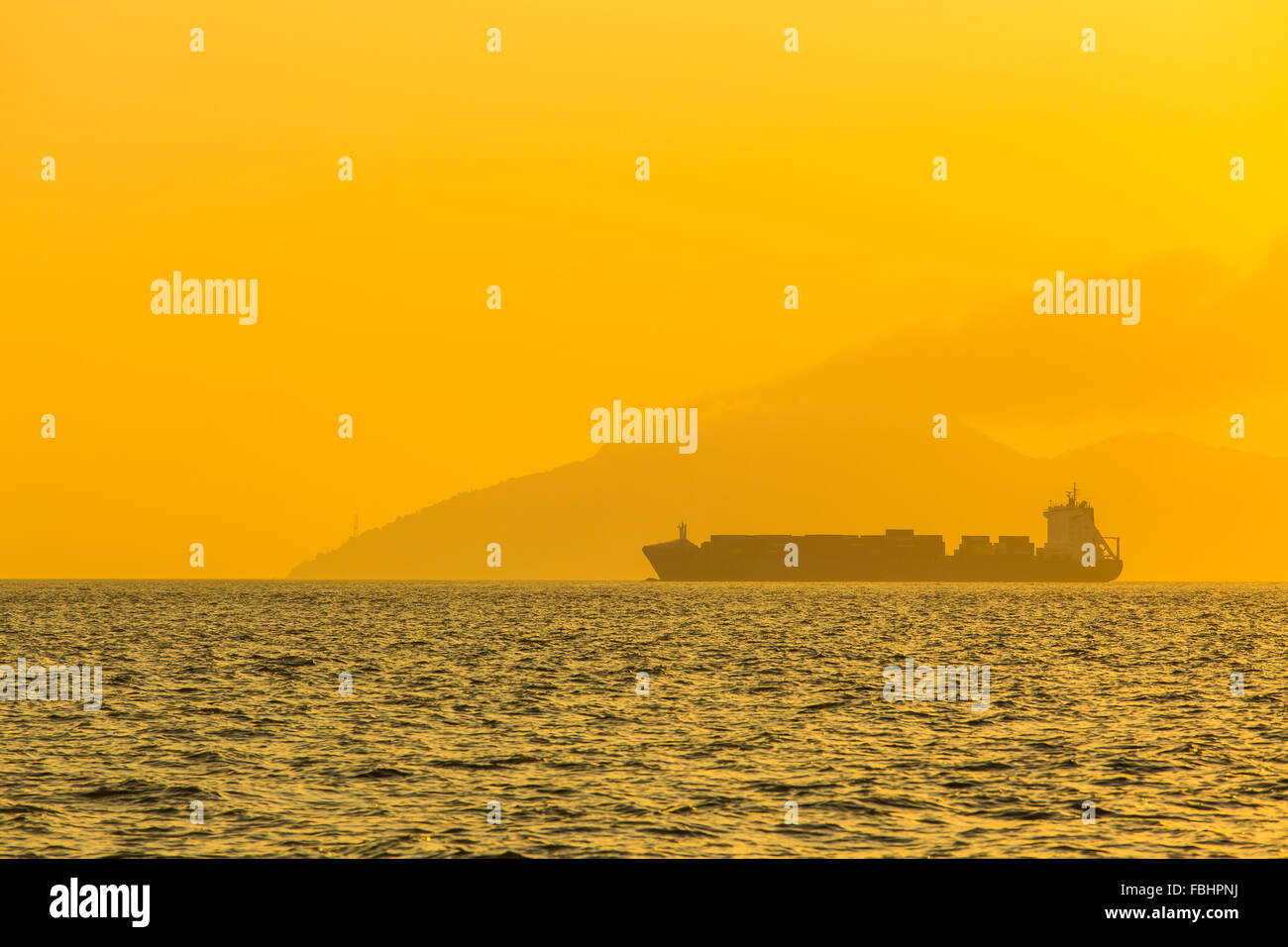 Cargo ship on sea at sunset Stock Photo - Alamy
