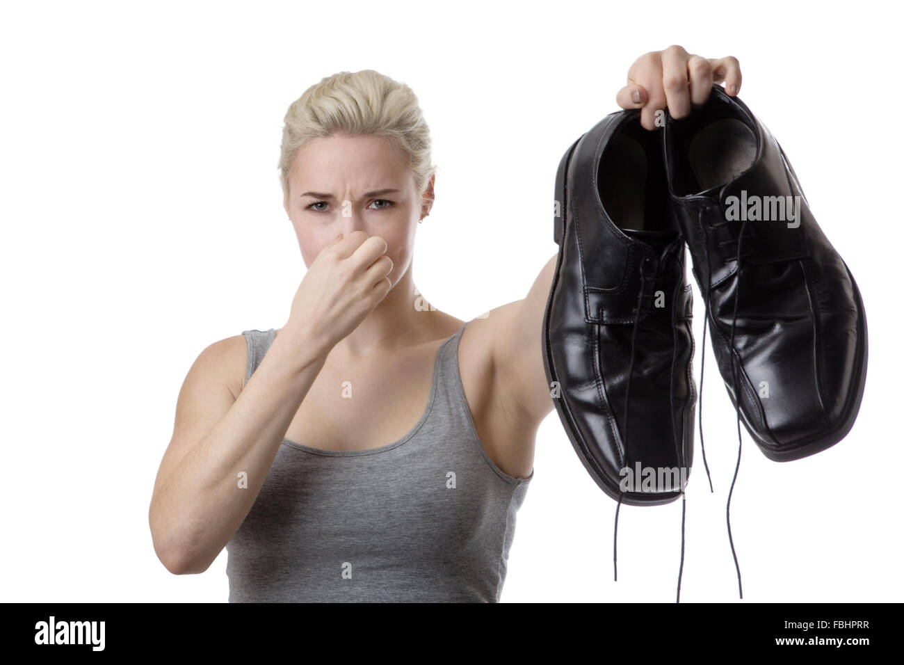woman holding up a pair of mens smelly shoes not looking very happy ...