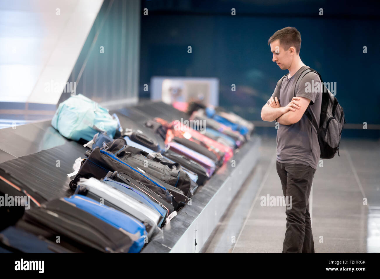 Young handsome man passenger in his 20s with carry-on backpack waiting ...