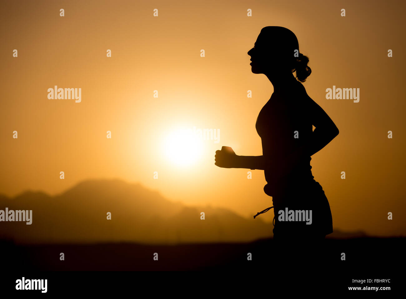 Profile silhouette of young sporty woman jogging against colorful ...