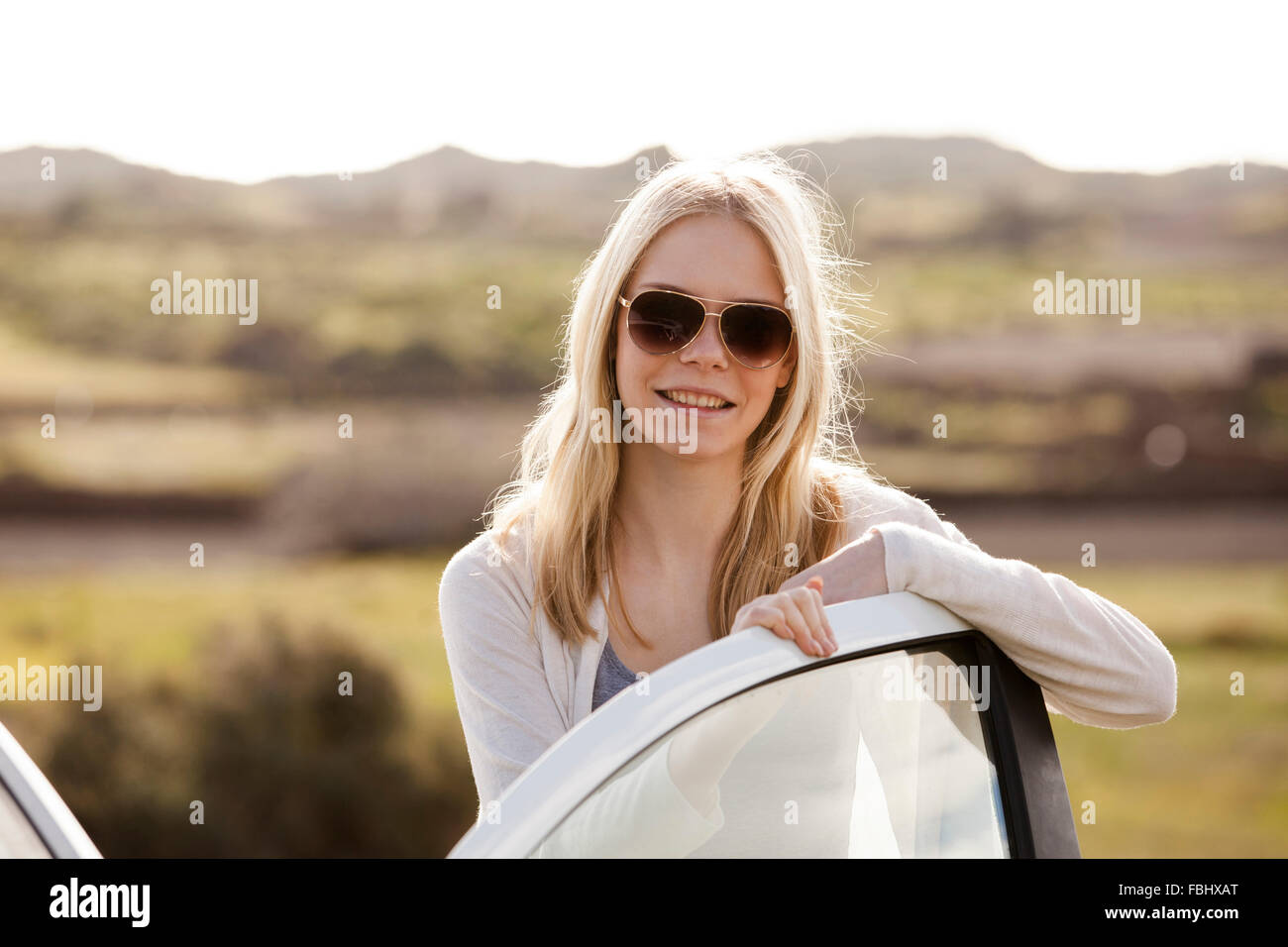 young woman leaning against car door Stock Photo - Alamy