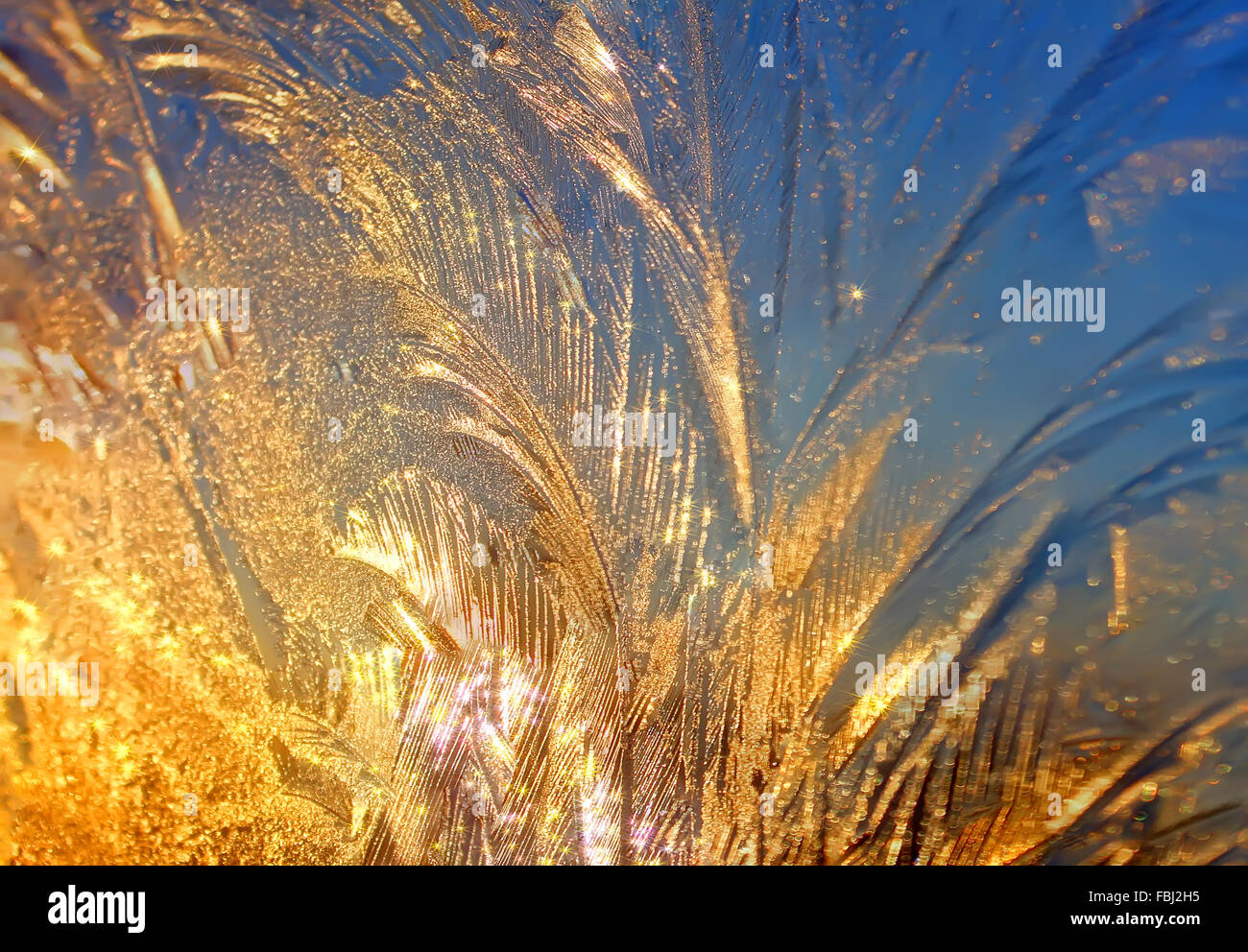 Sparkling ice-rich frosty pattern of thin ice on the window at sunset ...