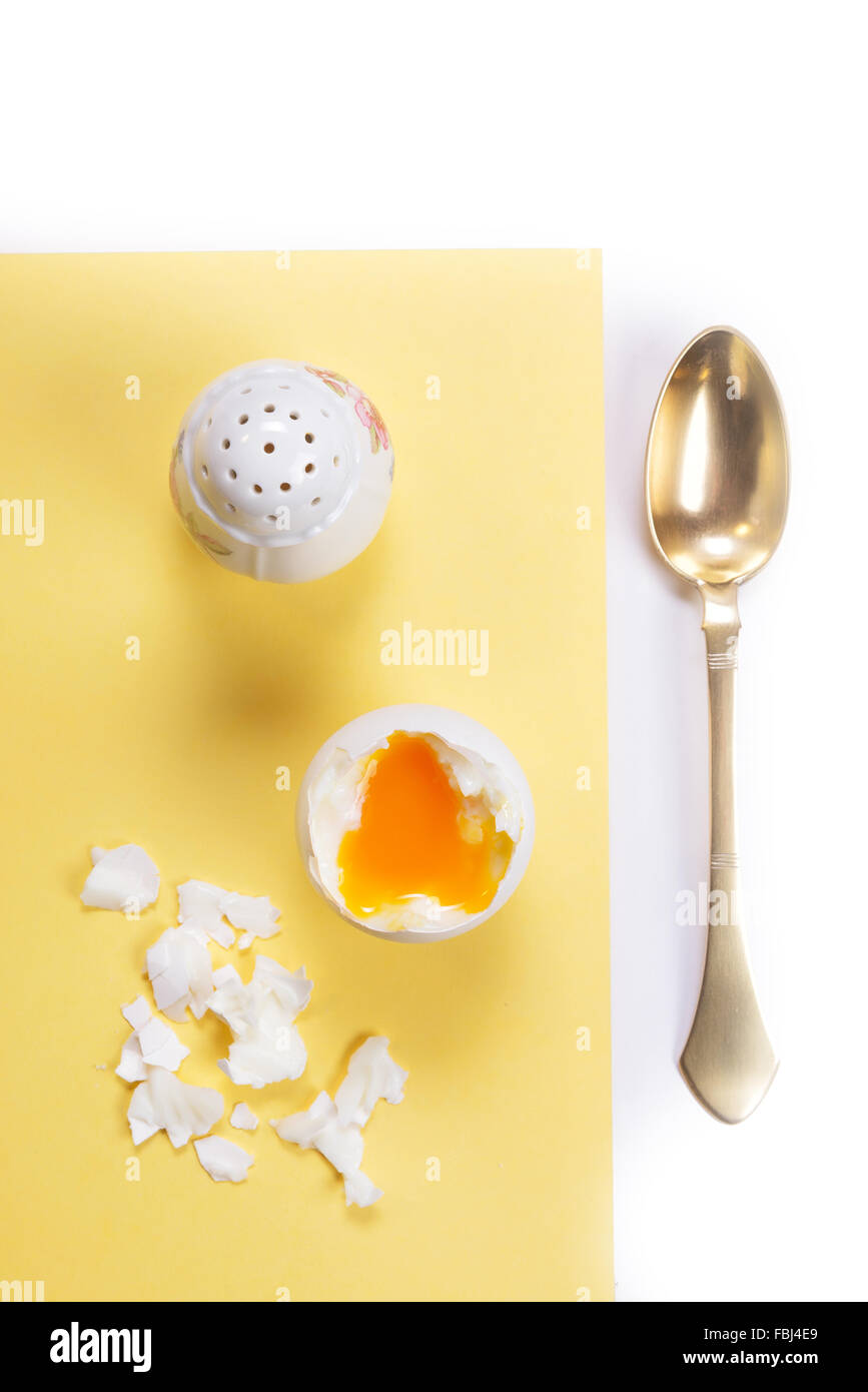 boiled egg, salt cellar and brass spoon on a yellow background Stock ...