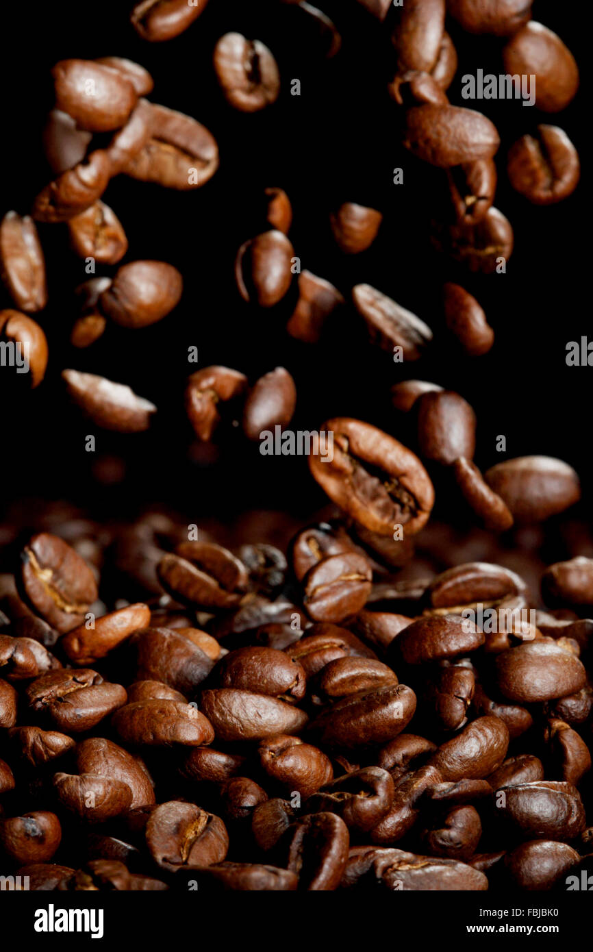 Falling roasted coffee beans on black background Stock Photo - Alamy