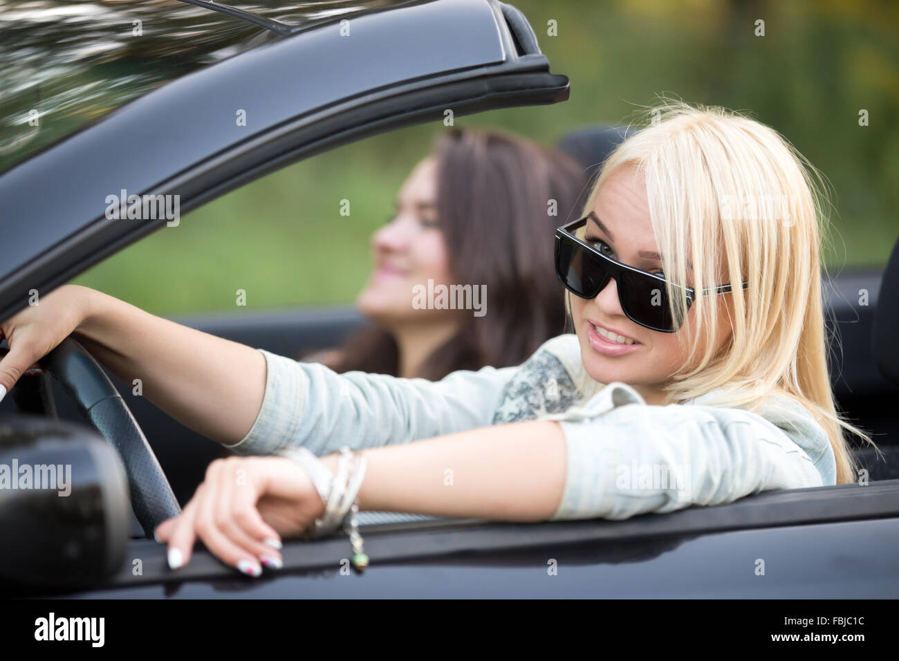 Portrait of beautiful confident smiling blond young woman in sunglasses ...