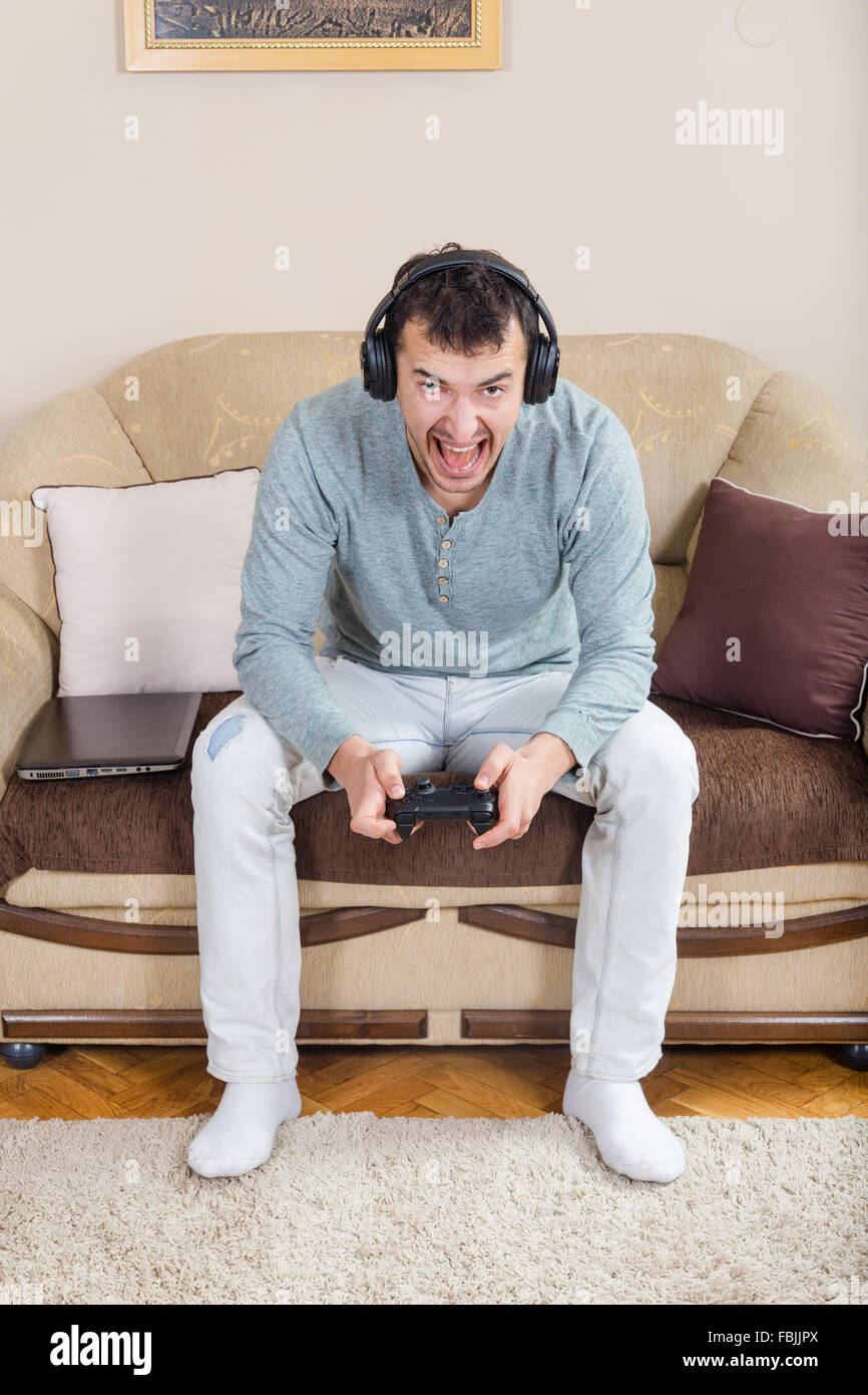 Angry young man with face reaction playing video games with wireless ...
