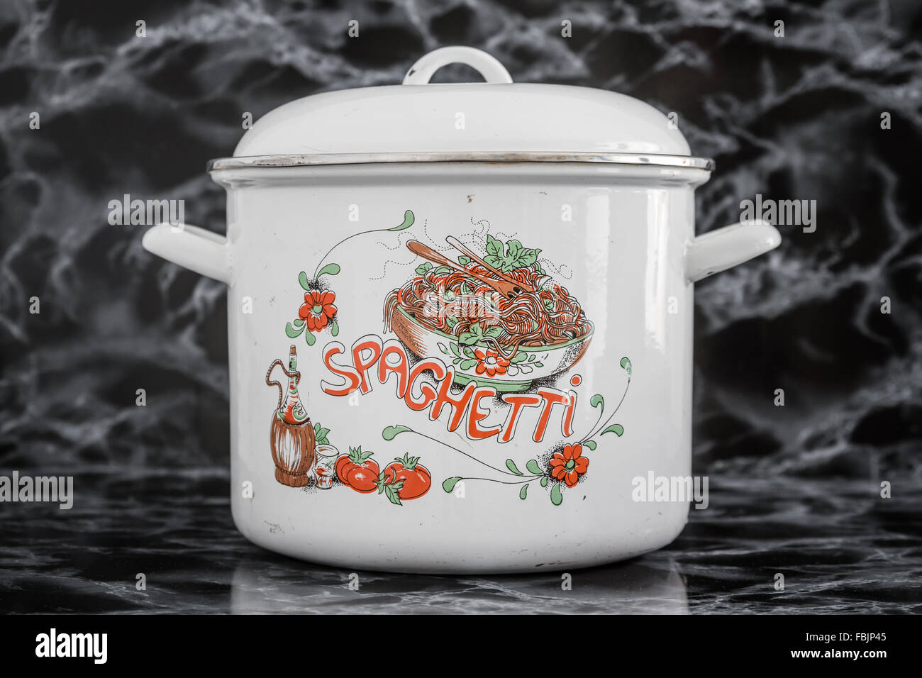 Big white vintage enamel saucepan with spaghetti design on black marble ...
